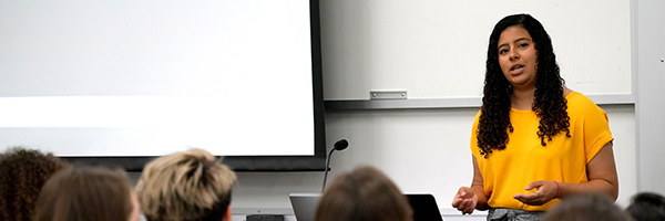 A young woman giving a presentation in front of an audience